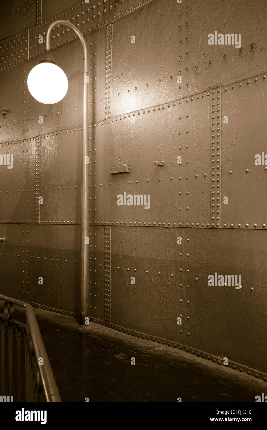 Riveted metal wall panels and lamp in a subway station, Paris, France ...