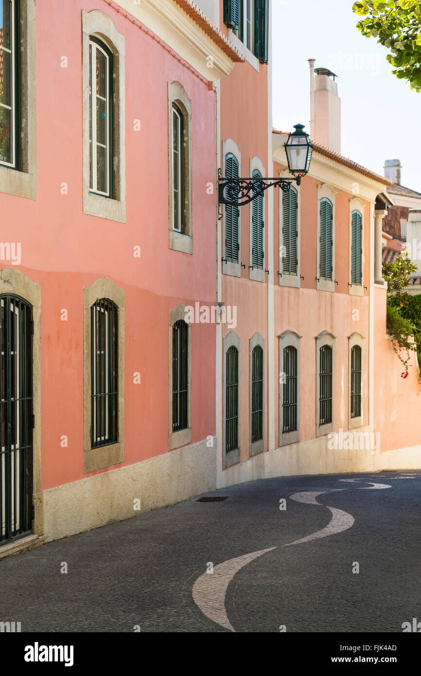 Colorful buildings line a typical cobblestone street in Cascais ...