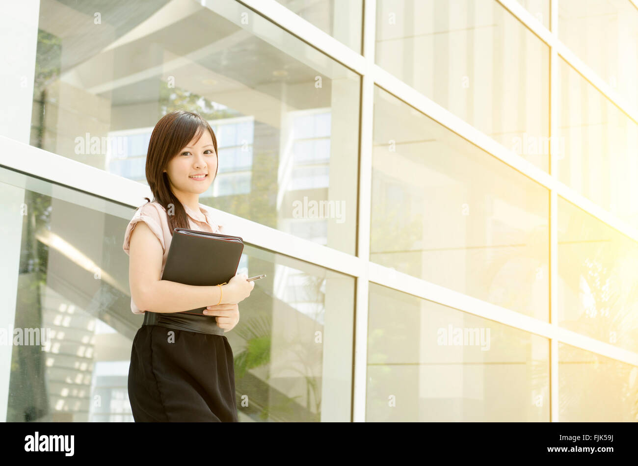Young Asian woman executive smiling and standing at an office ...