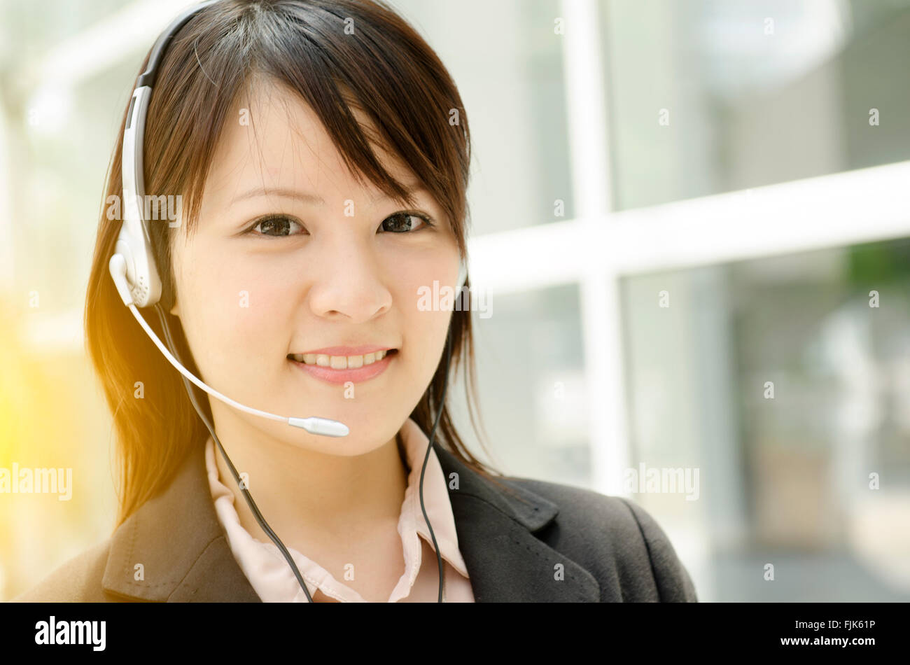 Portrait Of A Young Asian Female Receptionist With Headset Smiling At