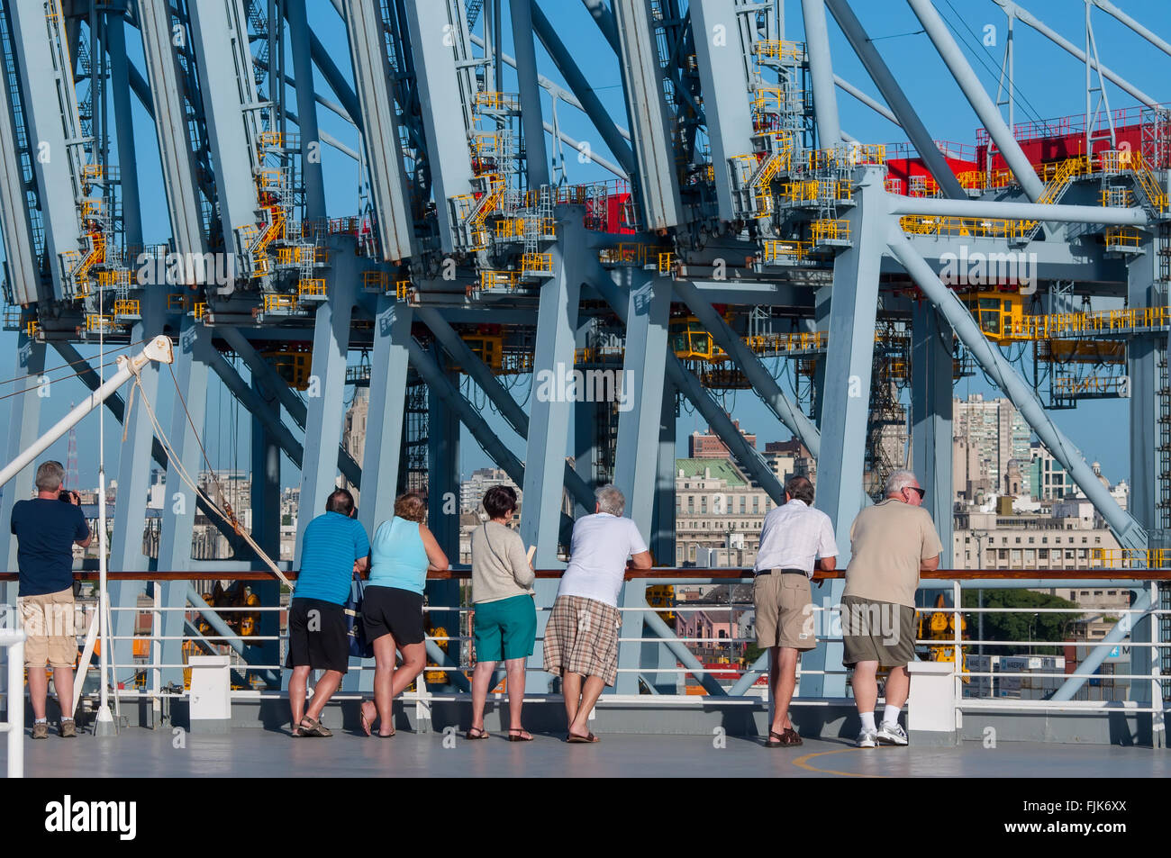 Passengers aboard a cruise ship standing on the deck and looking to a ...
