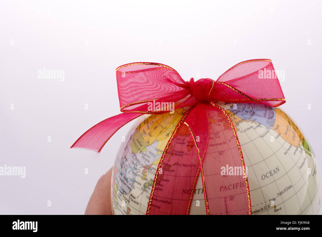 Globe tied with red ribbon on a white background Stock Photo - Alamy