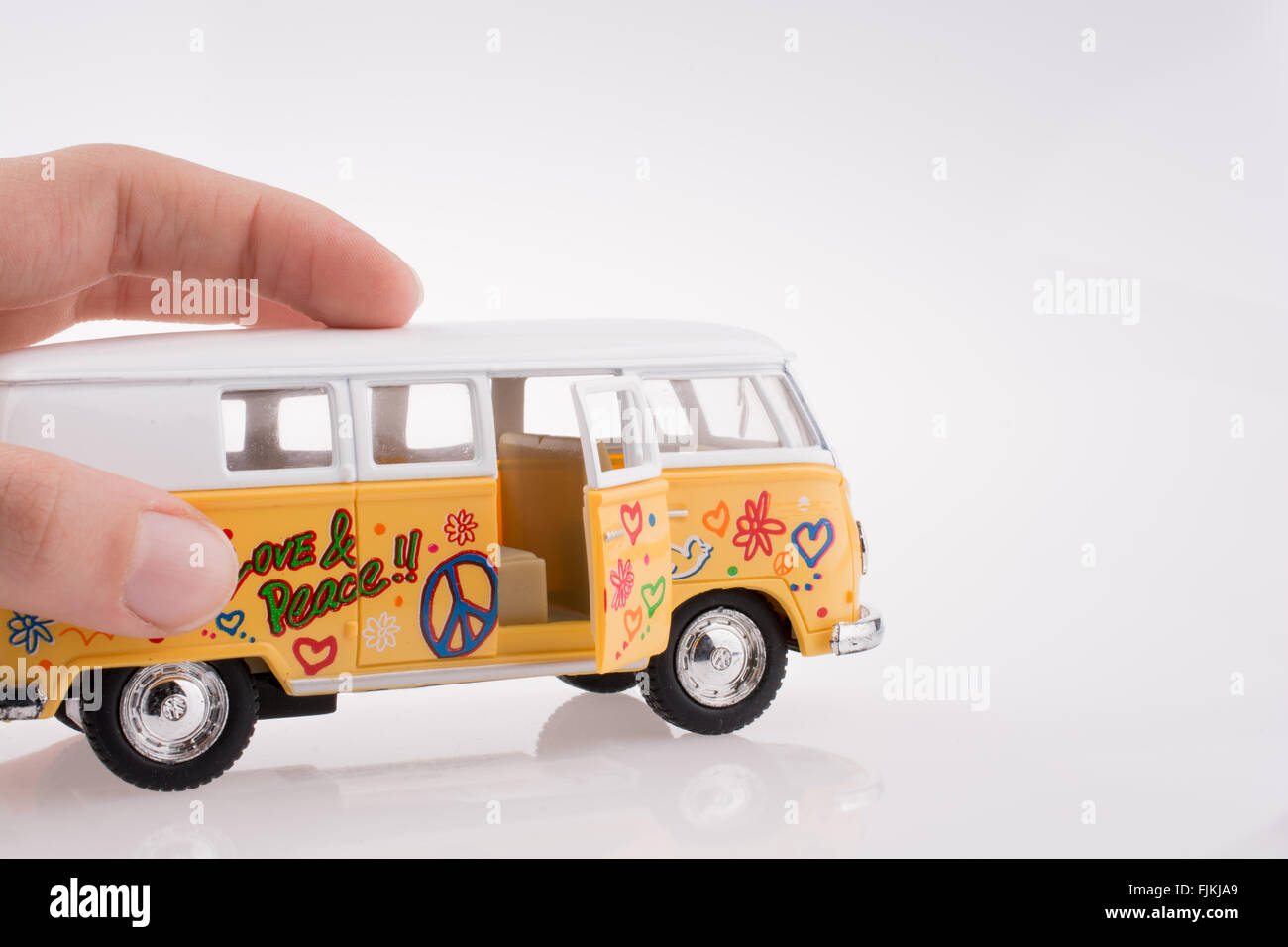 Hand holding a yellow Peace Van on a white background Stock Photo - Alamy