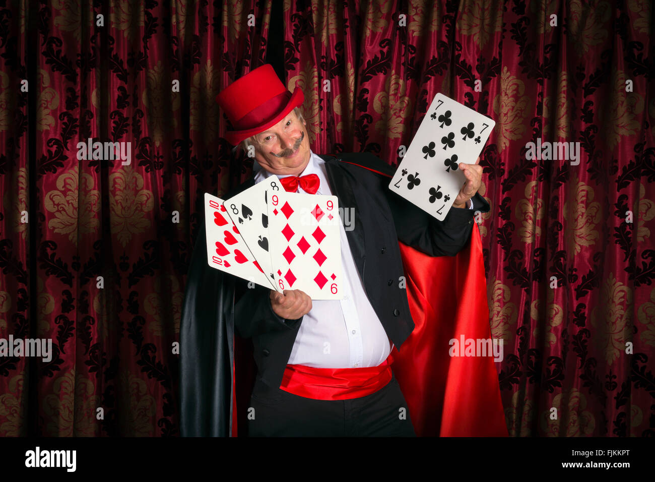 Mature magician on stage performing a magic trick with cards Stock ...