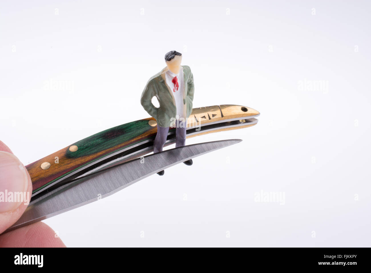 Hand holding a pocket knife near a human figure on a white background ...