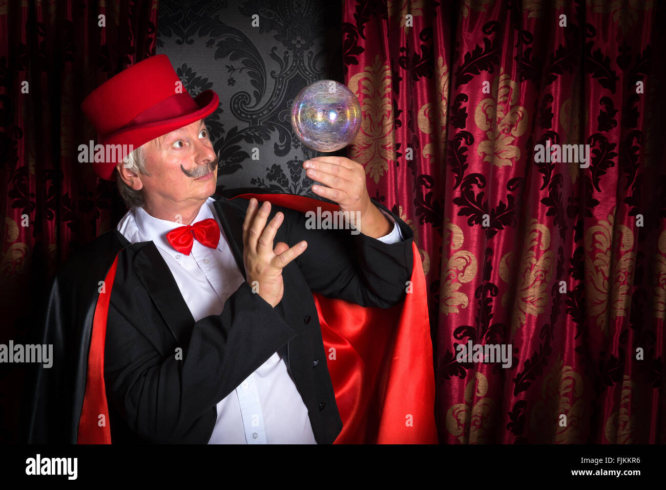 Senior magician performing on stage with a crystal ball Stock Photo - Alamy