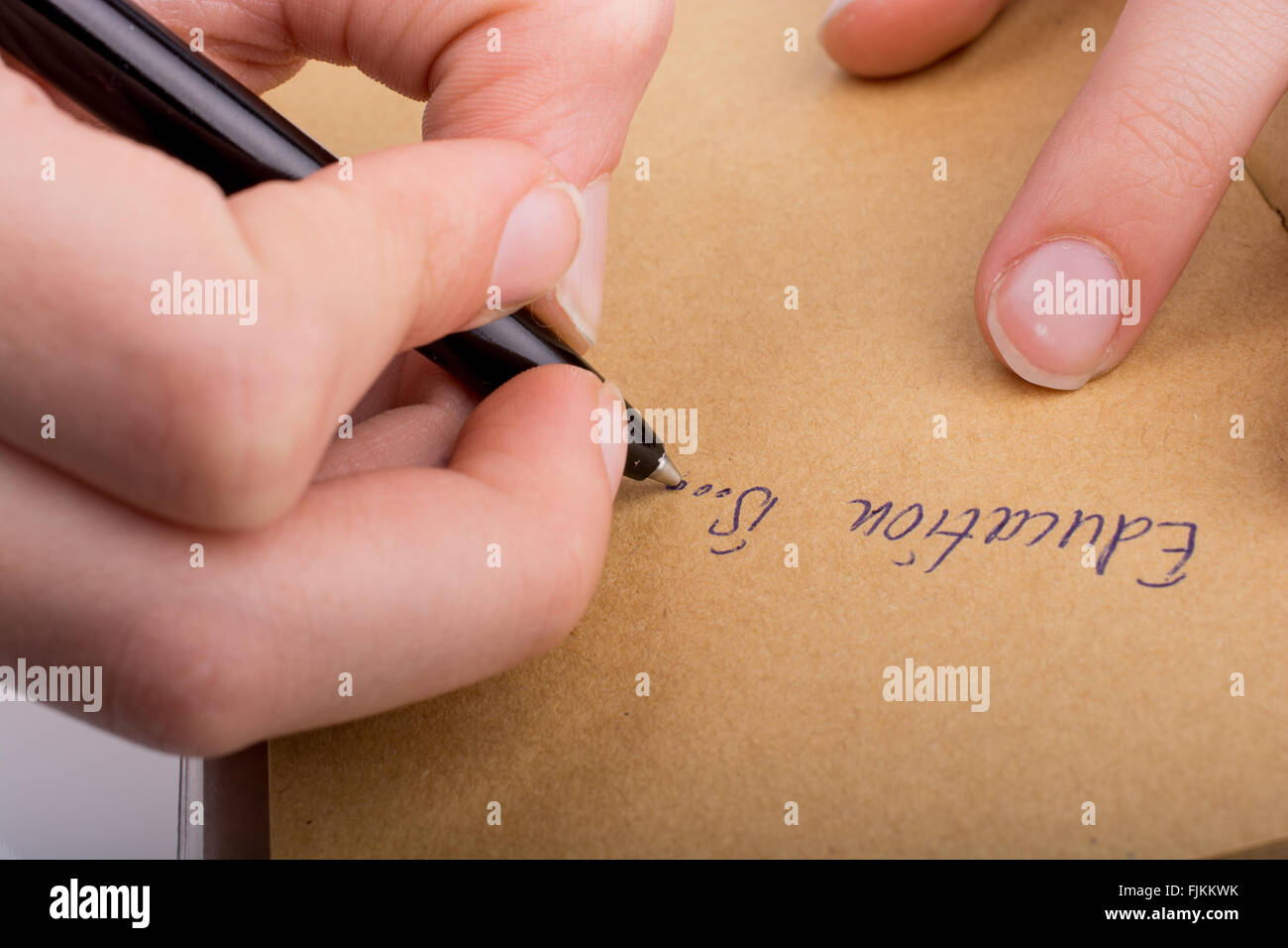 Hand writing 'Education is...' on a notebook Stock Photo - Alamy