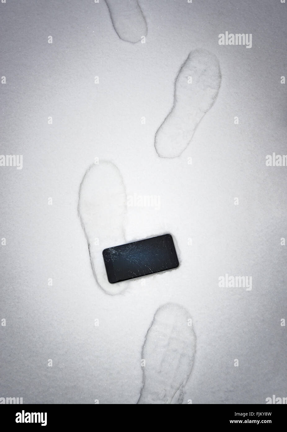 Someone stepped on a phone and damaged screen. Device in snow with foot ...