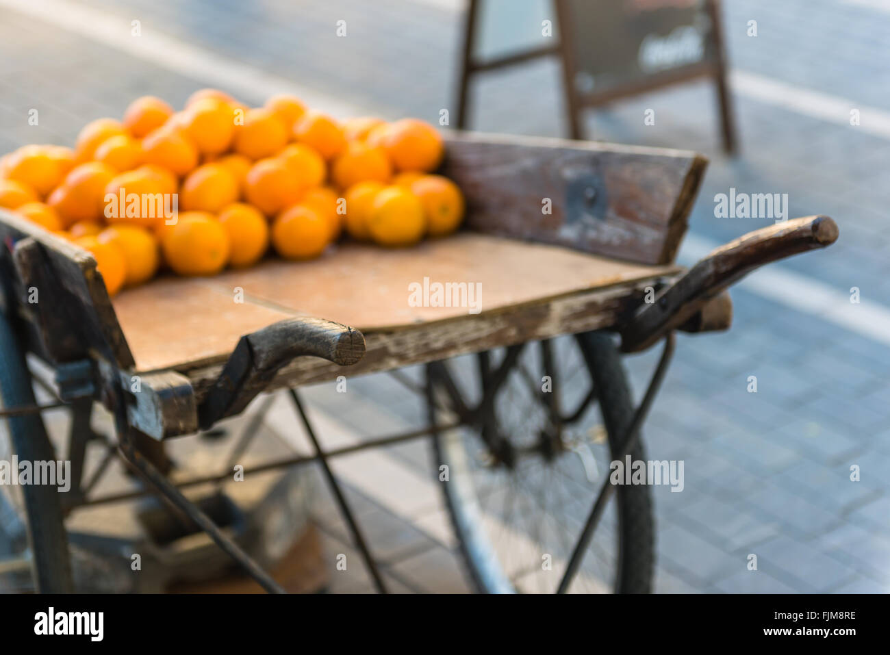 Fresh oranges on vintage wooden cart in the town. Shot with a selective ...