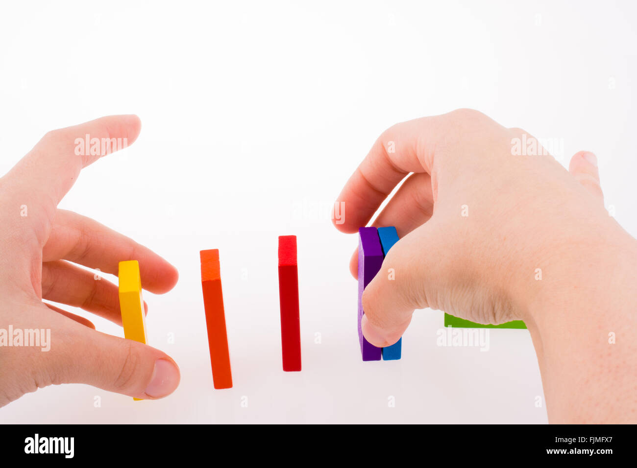 Hand playing with colored domino on white background Stock Photo - Alamy