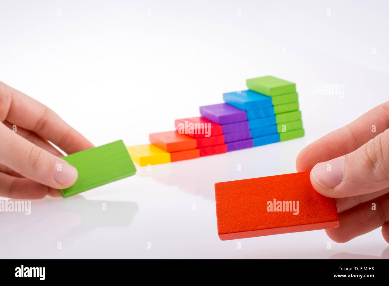 Hand playing with colored domino on white background Stock Photo - Alamy