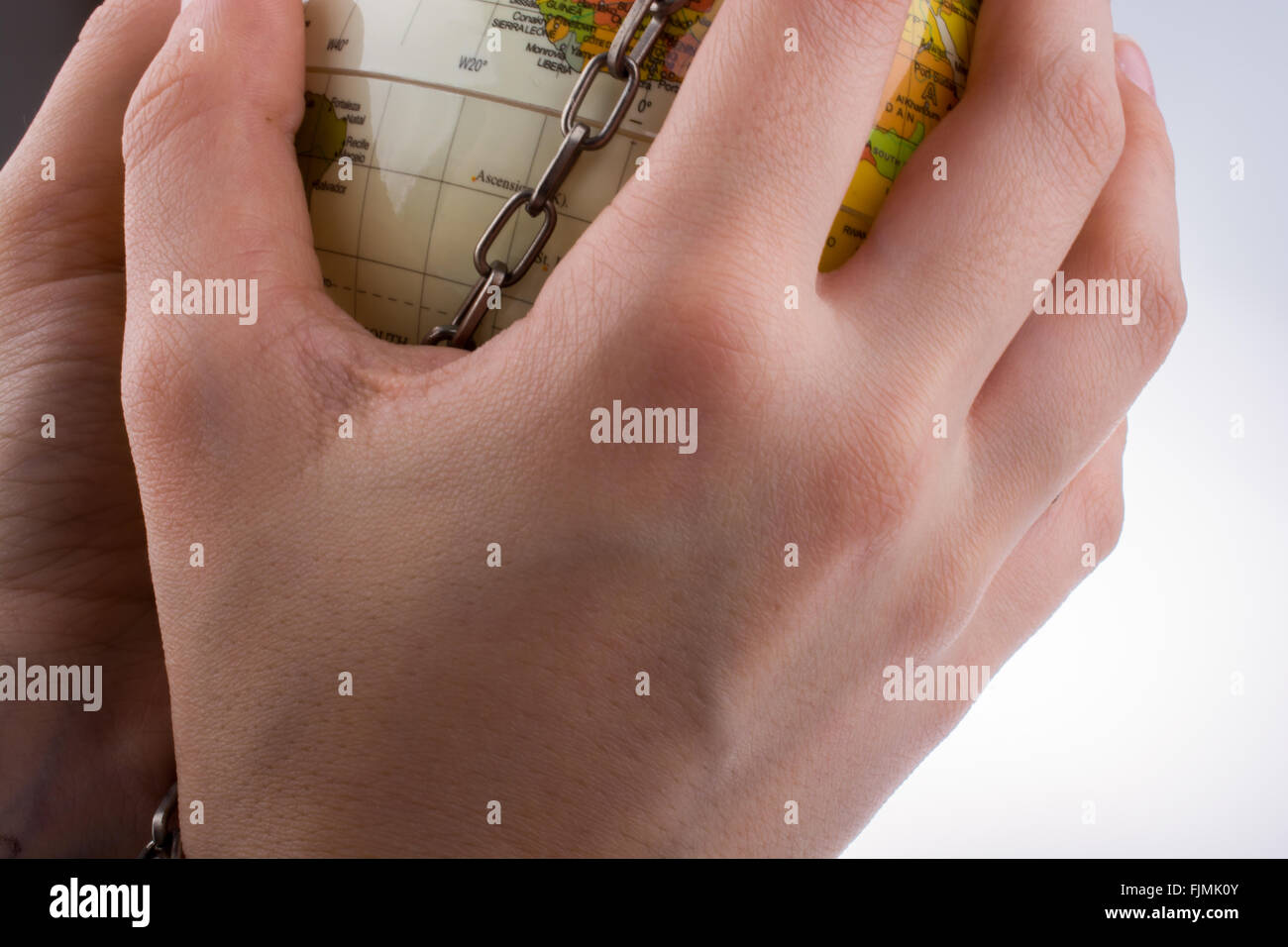 Hand holding a globe in chains Stock Photo - Alamy