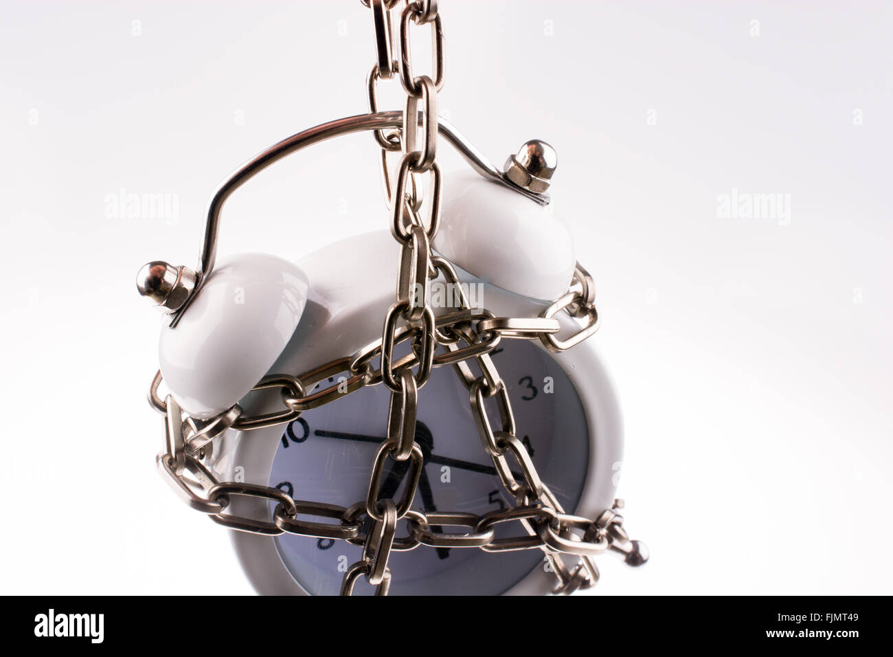 White color alarm clock in chain on a white background Stock Photo - Alamy