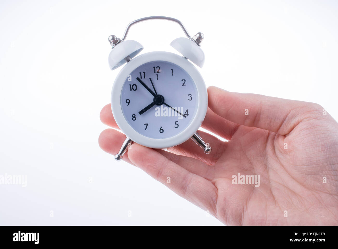 Alarm clock in hand on a white background Stock Photo - Alamy