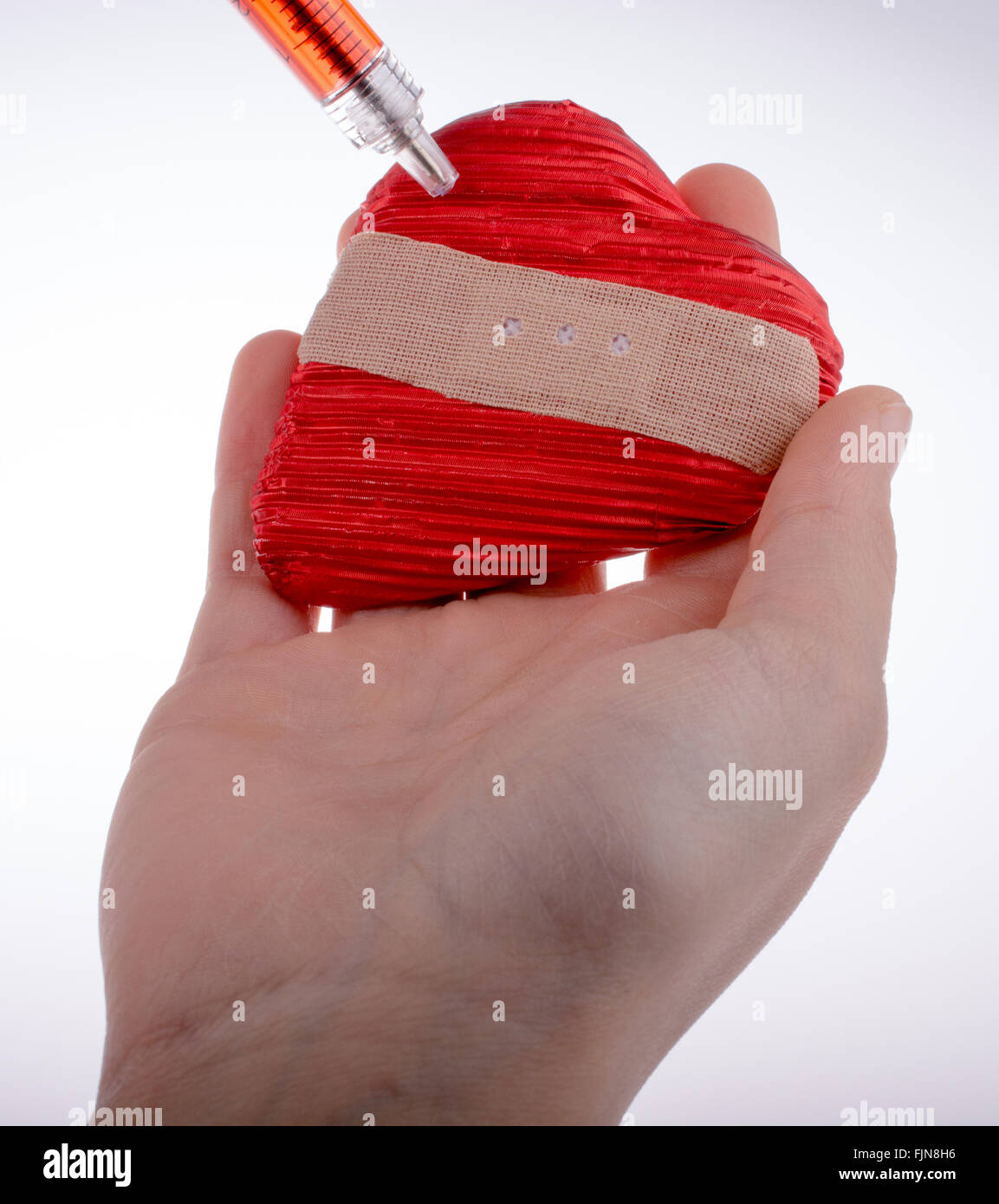 Hand injecting love into heart in plaster on white background Stock ...