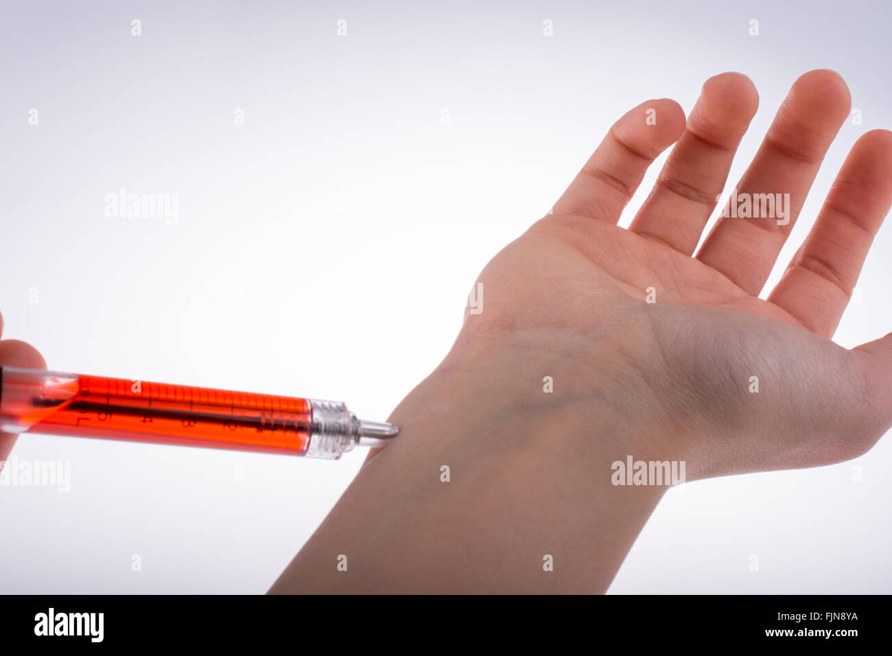 hand holding injection to itself on a white background Stock Photo - Alamy