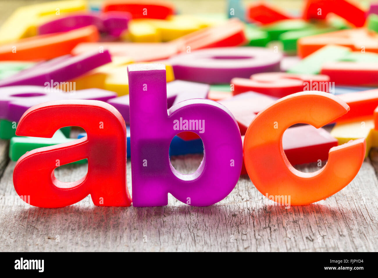 ABC spelling and pile of colorful plastic letters on wooden background ...