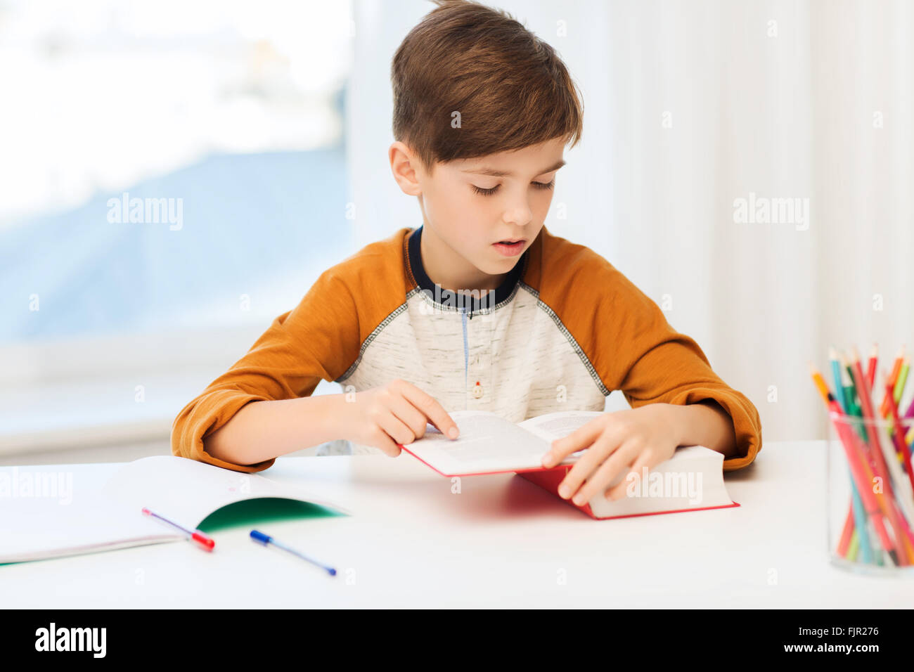 student boy reading book or textbook at home Stock Photo - Alamy