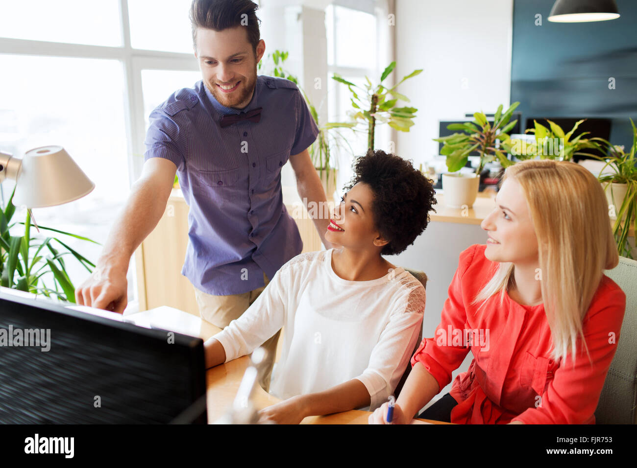 happy creative team with computer in office Stock Photo - Alamy