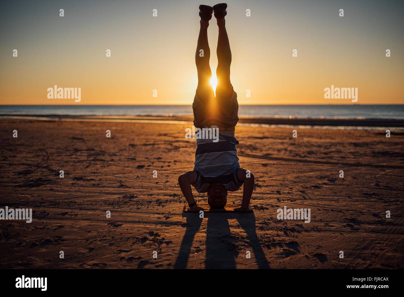 Man performing handstand beach sunset balance hi-res stock photography ...