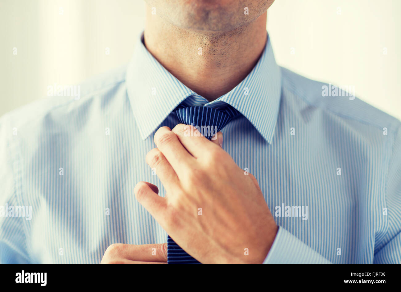 close up of man in shirt adjusting tie on neck Stock Photo - Alamy