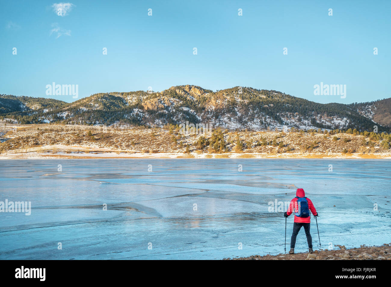male hiker at a shore of frozen Horsetooth Reservoir near Fort Collins ...