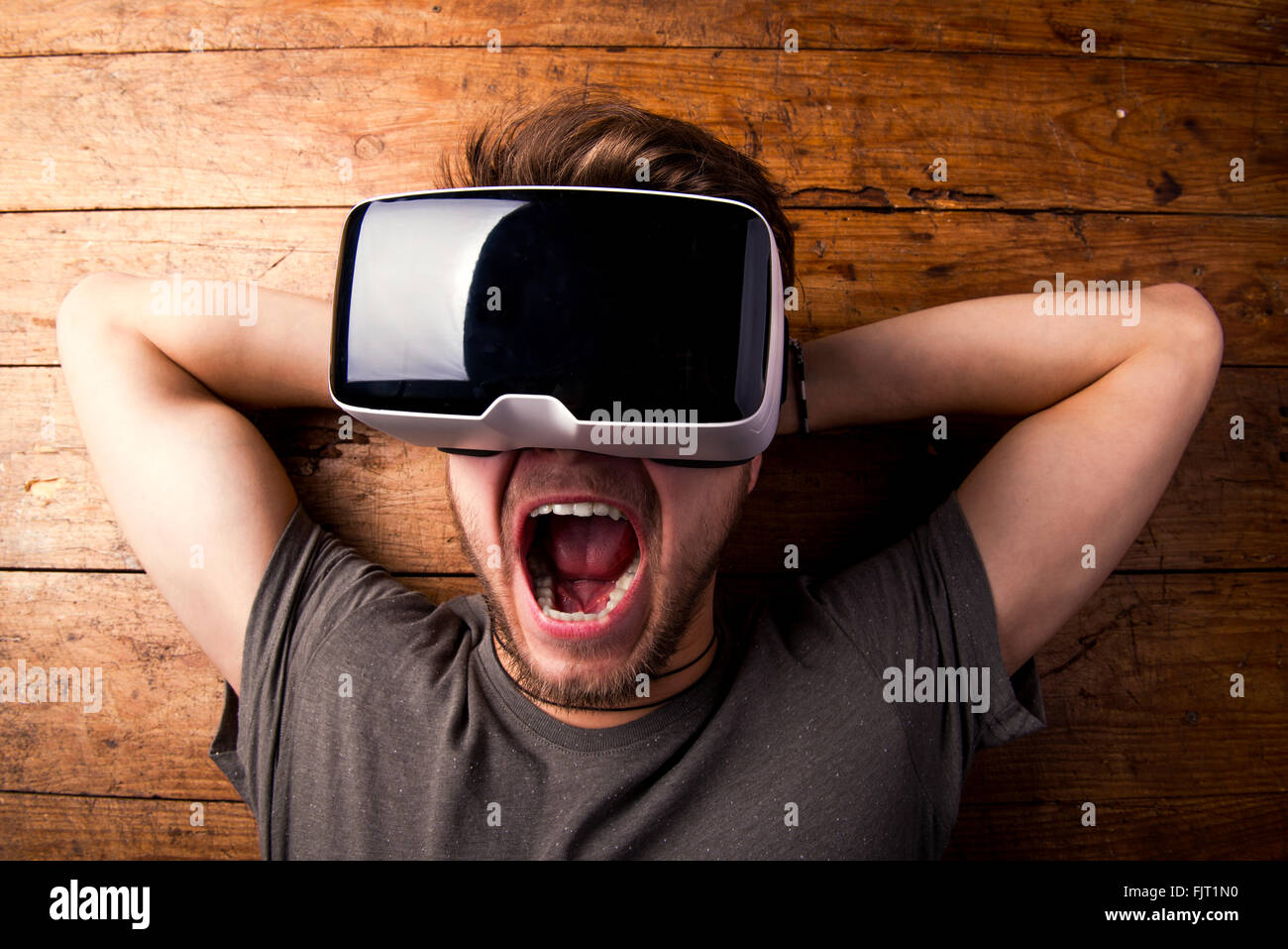 Man wearing virtual reality goggles. Studio shot, wooden background ...