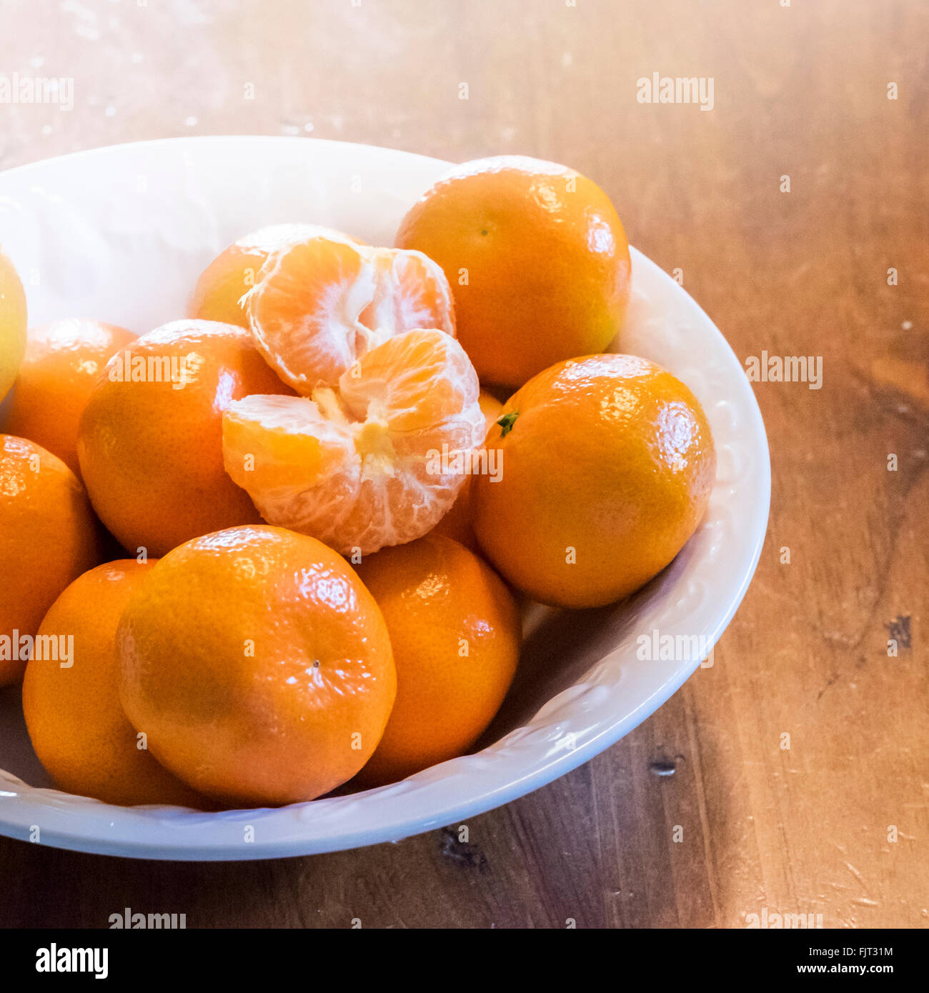 Mandarin oranges, Citrus reticulata, with one peeled in a white bowl ...