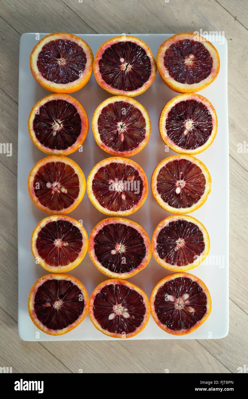 Ruby red blood oranges cut in half on a white platter Stock Photo - Alamy