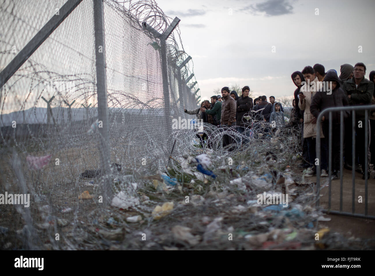 Refugees standing in front of the border fence in a refugee camp in ...