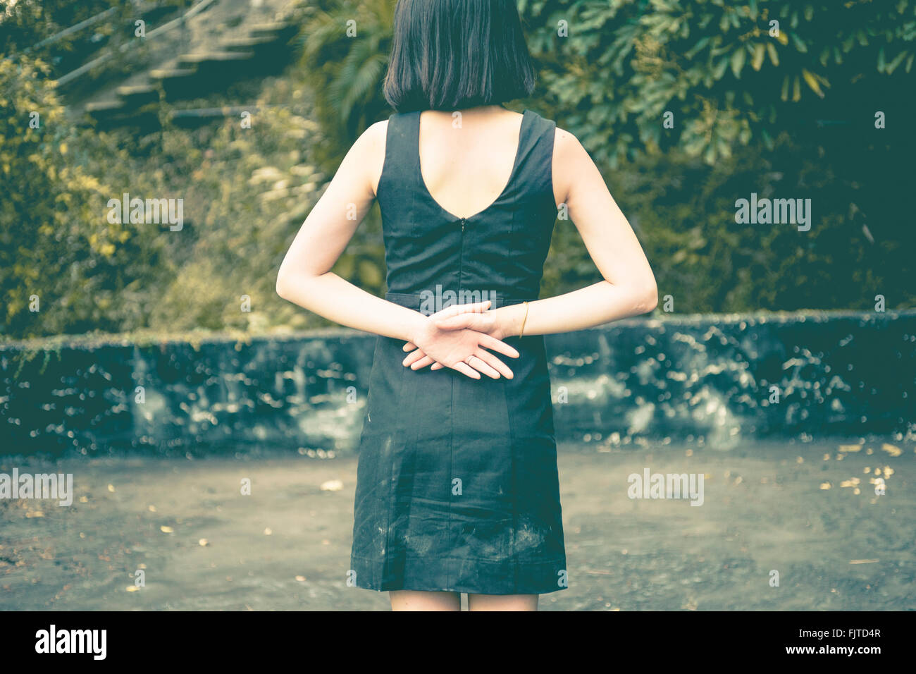 Woman With Hands Behind Back Standing Outdoors Stock Photo - Alamy