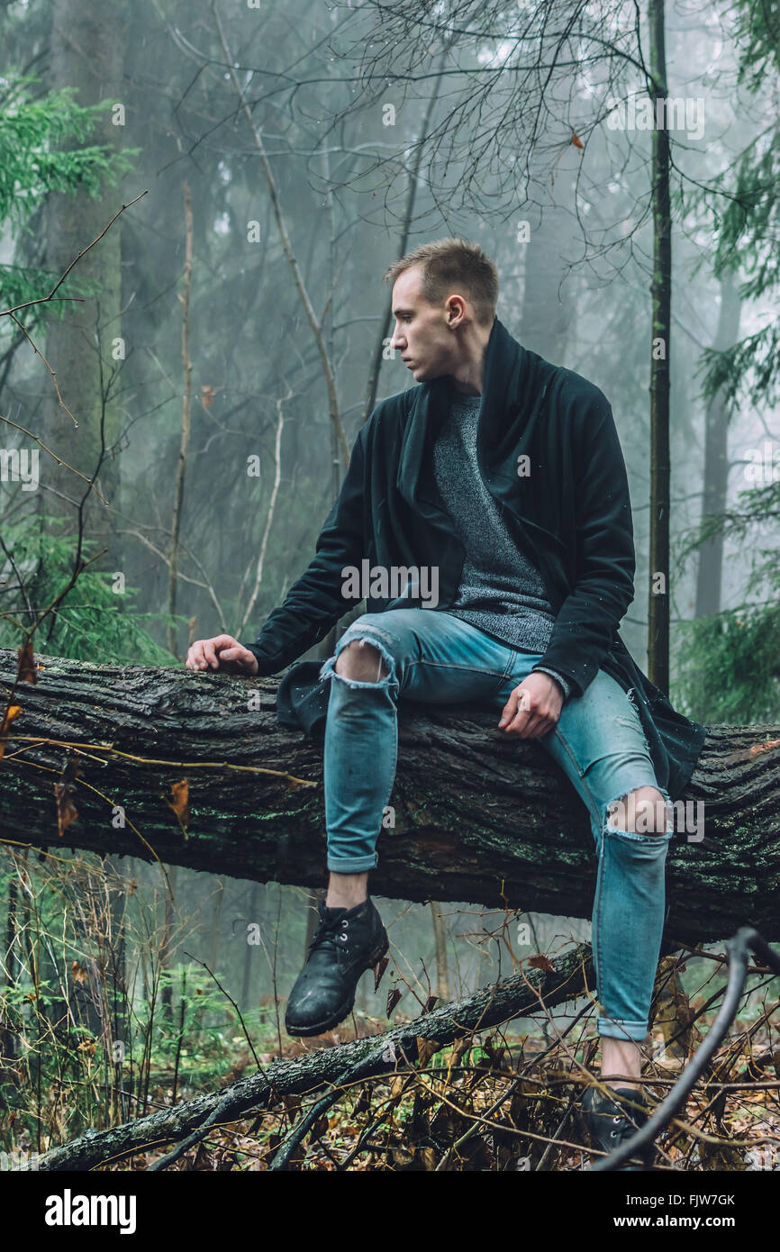 Handsome Man Sitting On Fallen Tree In Forest Stock Photo - Alamy
