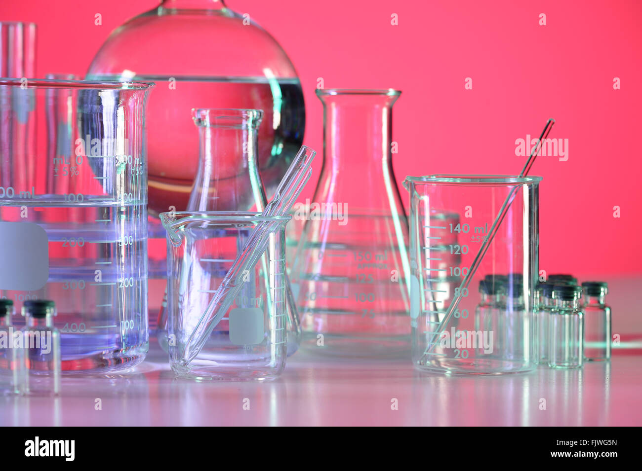 Laboratory glassware on reflective table with red background Stock ...