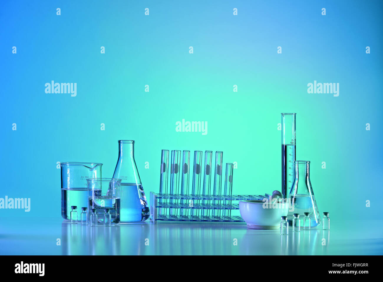 Laboratory glassware on table with colored background Stock Photo - Alamy