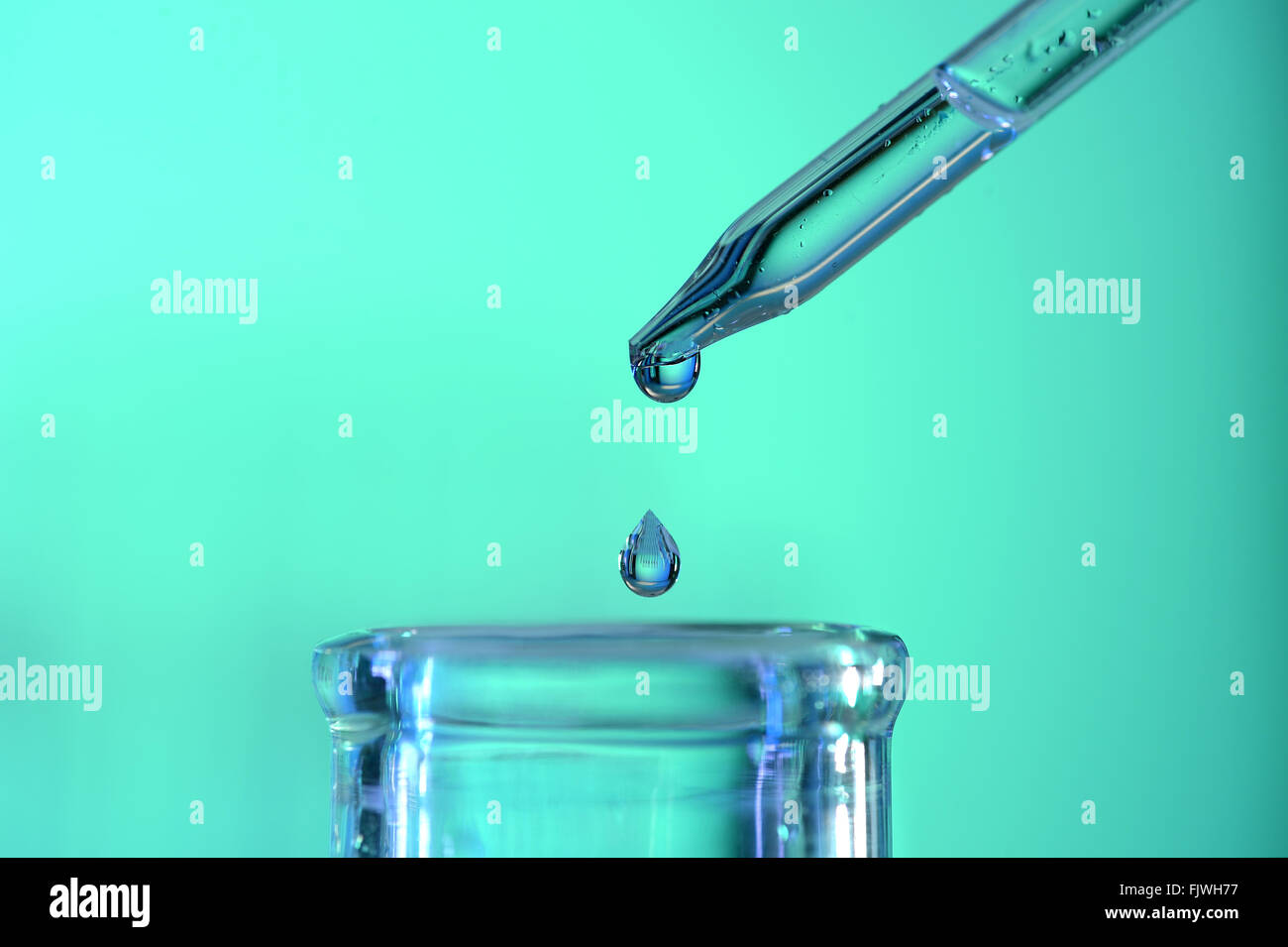 Laboratory pipette dripping liquid into a container over green ...