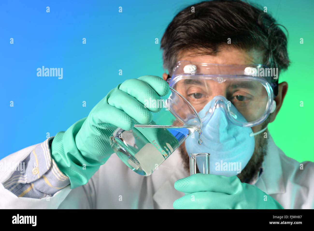 Scientist pouring liquid from beaker to test tube inside laboratory ...