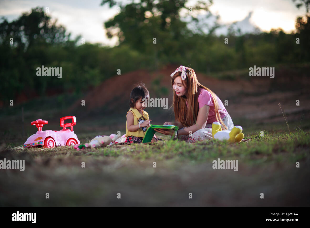 Mother teaches reading book to child daughter Stock Photo - Alamy