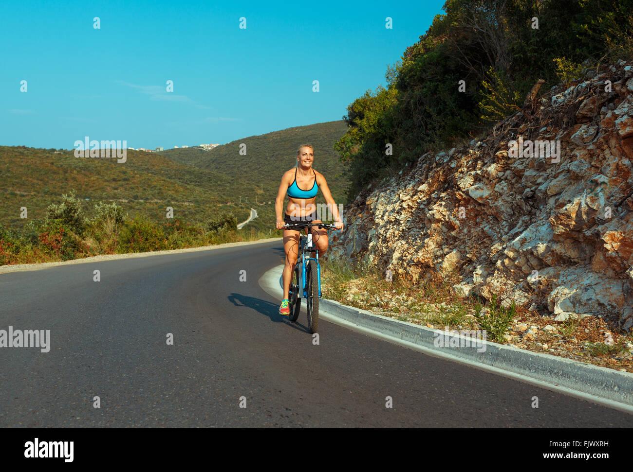 Happy woman cyclist riding a bike on a mountain road Stock Photo - Alamy