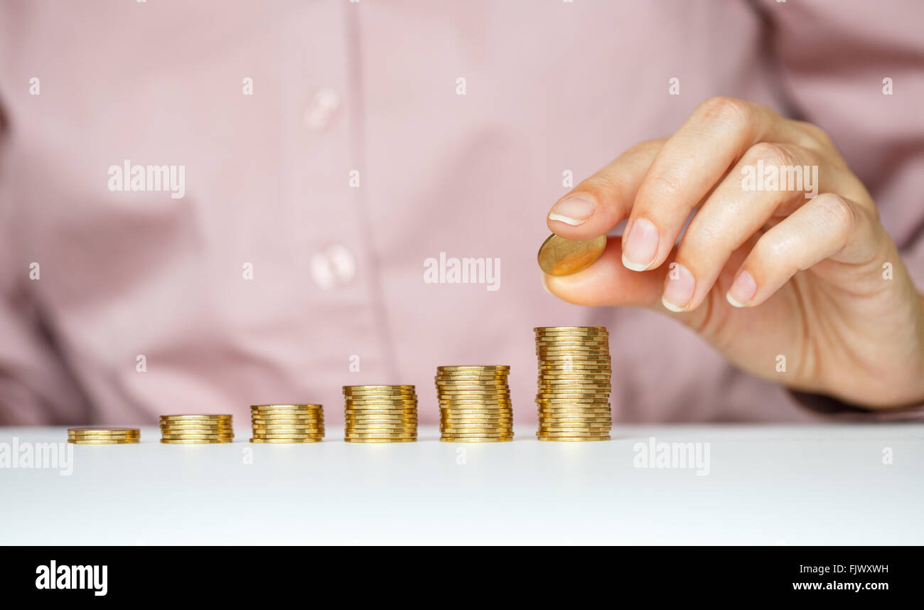 Savings, female hand stacking gold coins into increasing columns Stock ...