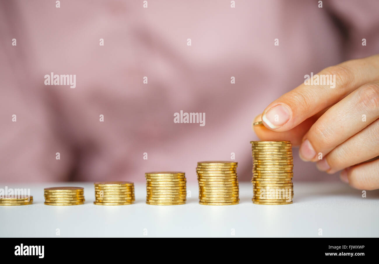 Savings, female hand stacking gold coins into increasing columns Stock ...
