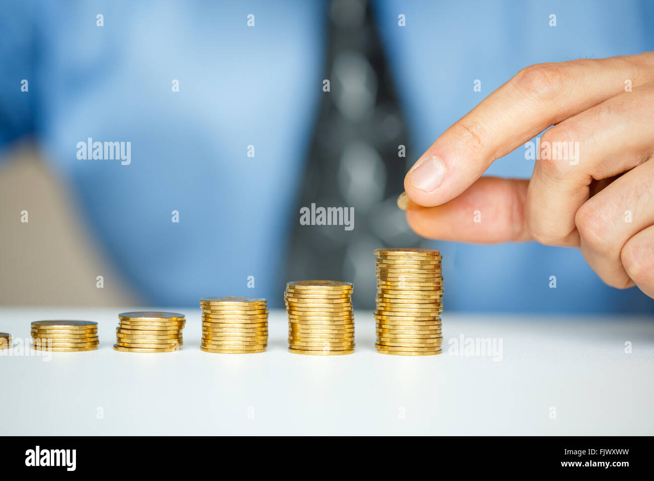 Savings, male hand stacking gold coins into increasing columns Stock ...