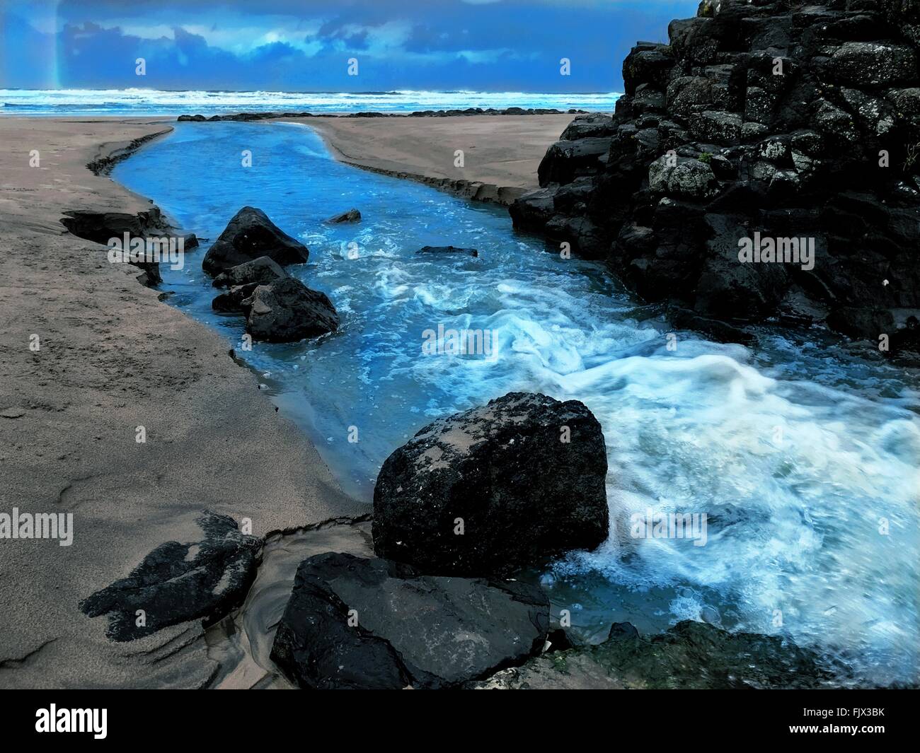 Rocks By Water At Beach Stock Photo - Alamy