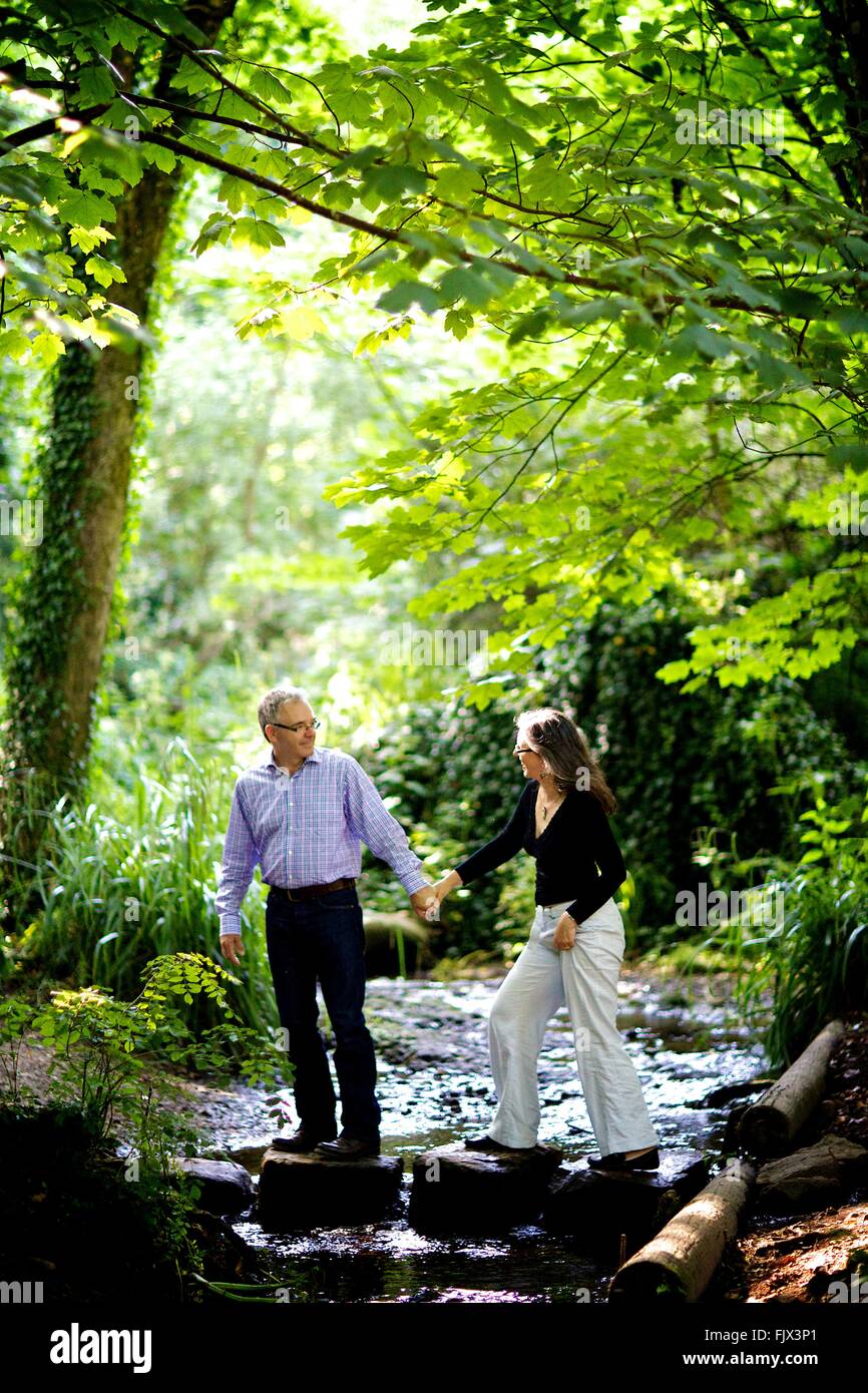 Couple in woods surrounded by nature crossing the water, bridge ...