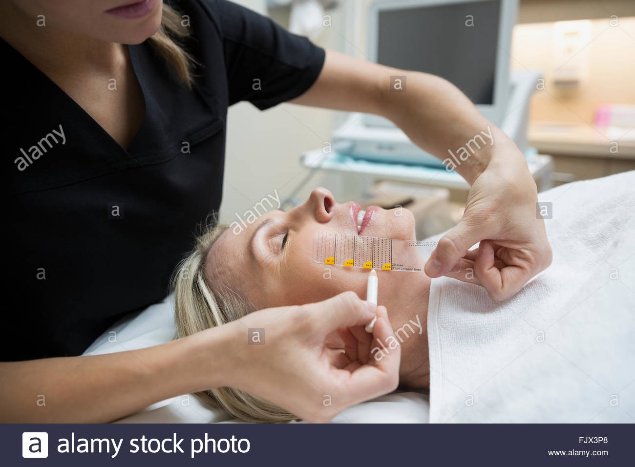Aesthetic technician measuring and marking womans face Stock Photo - Alamy