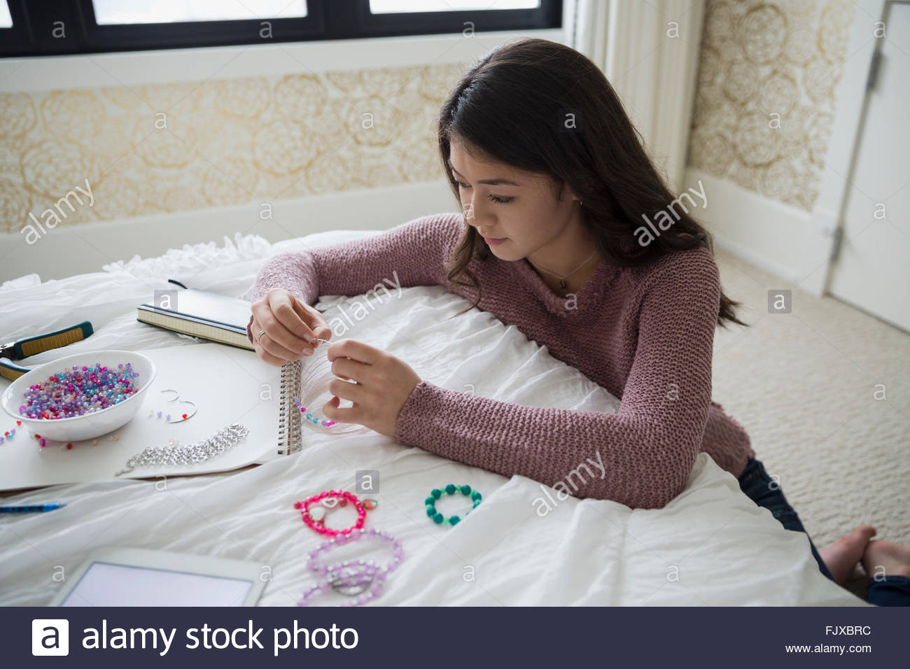 Teenage girl making jewelry on bed Stock Photo - Alamy