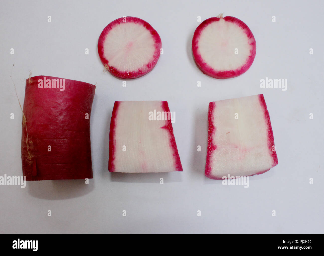 Raphanus sativus, red long radish, sliced to show white flesh, commonly ...