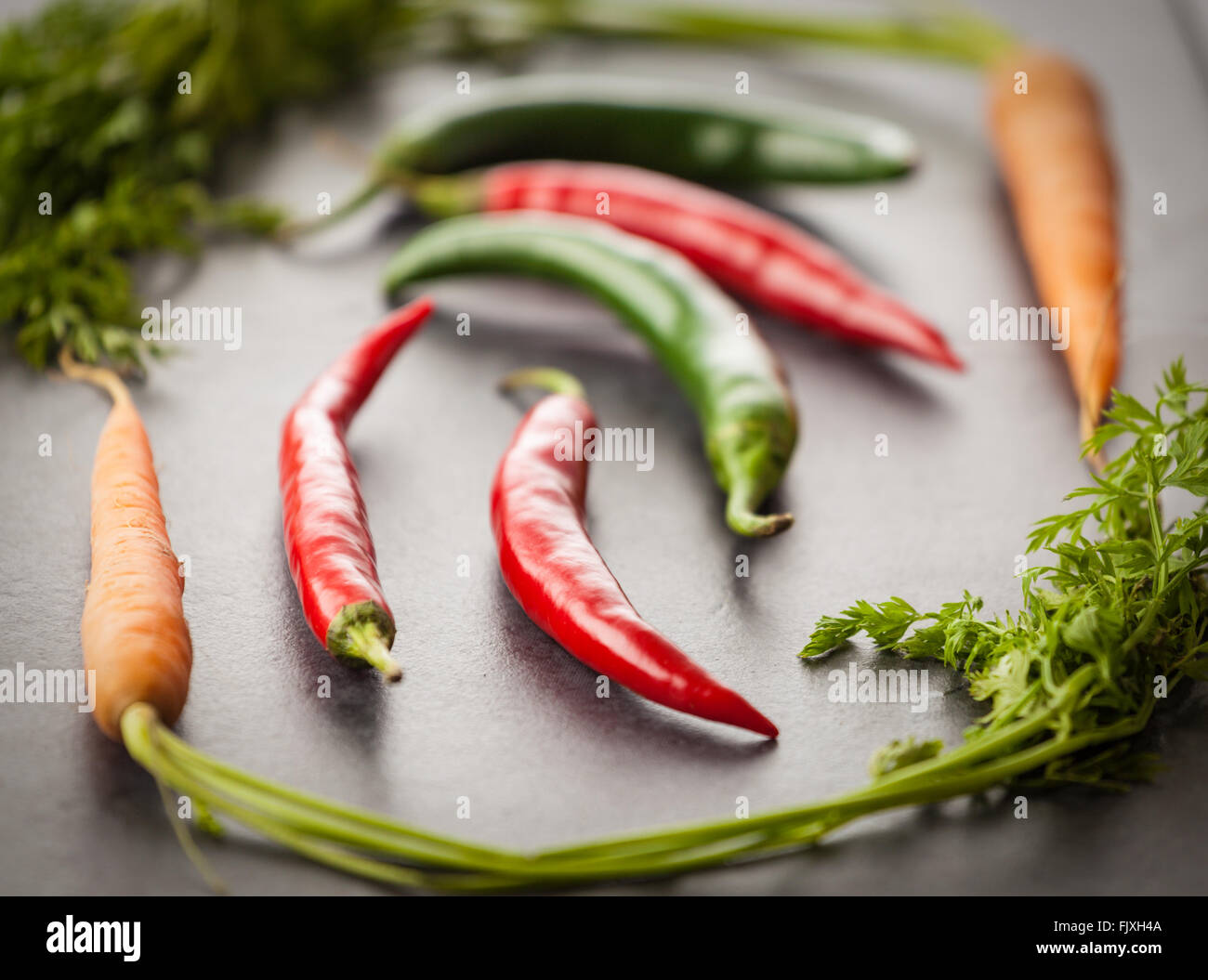 Dutch sweet carrots and hot chilli peppers on stone background. Shallow ...