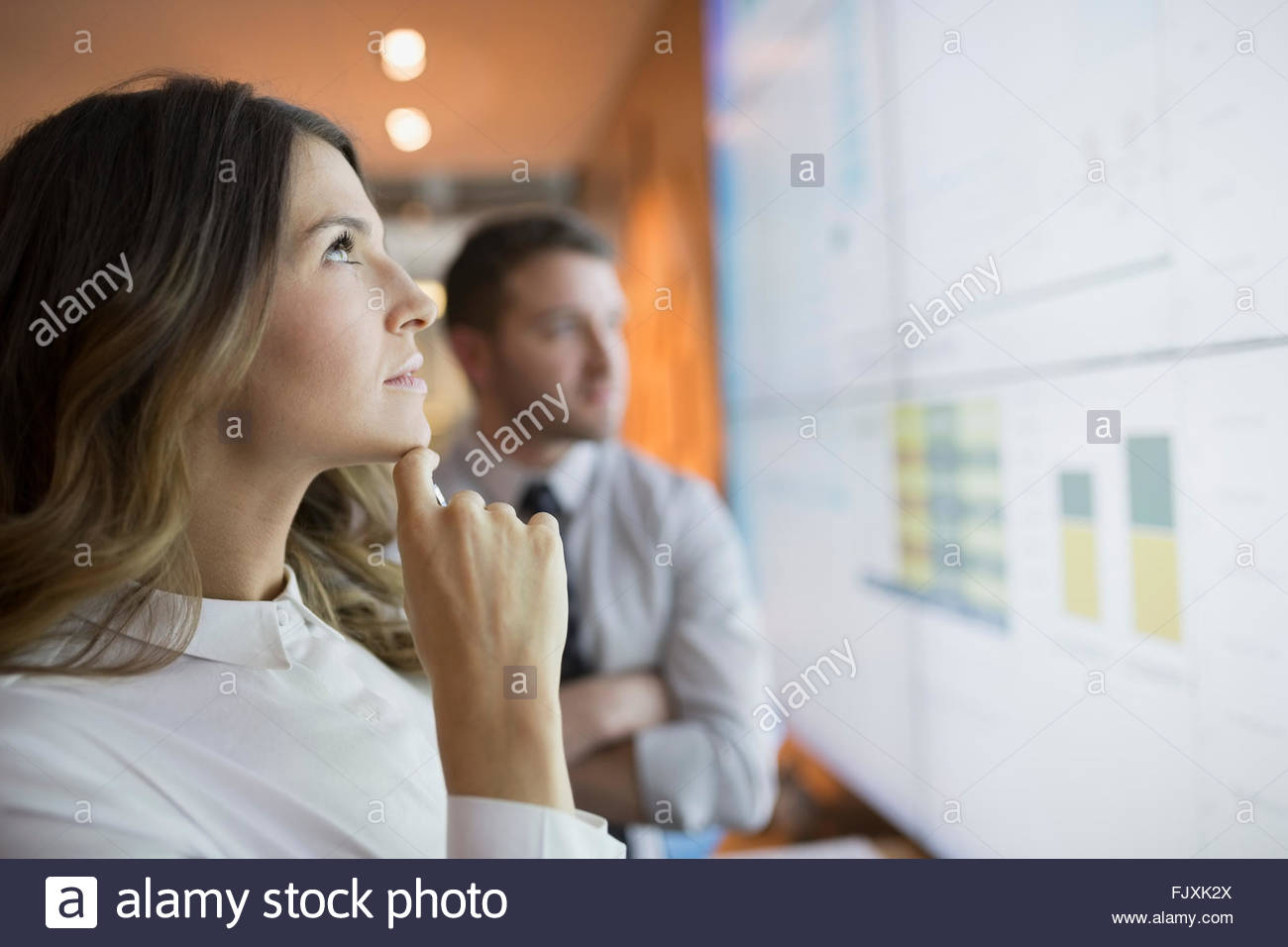 Focused businesswoman looking up at projection screen Stock Photo - Alamy