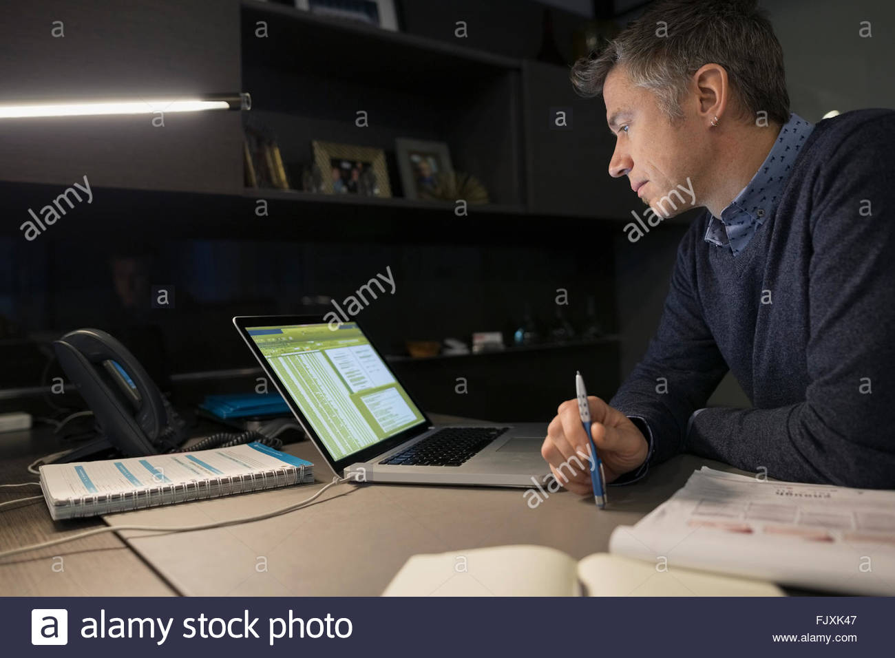 Businessman working late at laptop in office Stock Photo - Alamy
