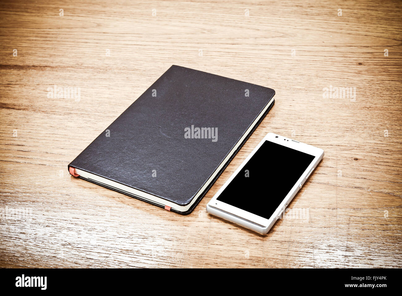Black leather business diary and Mobile phone on wood table background ...